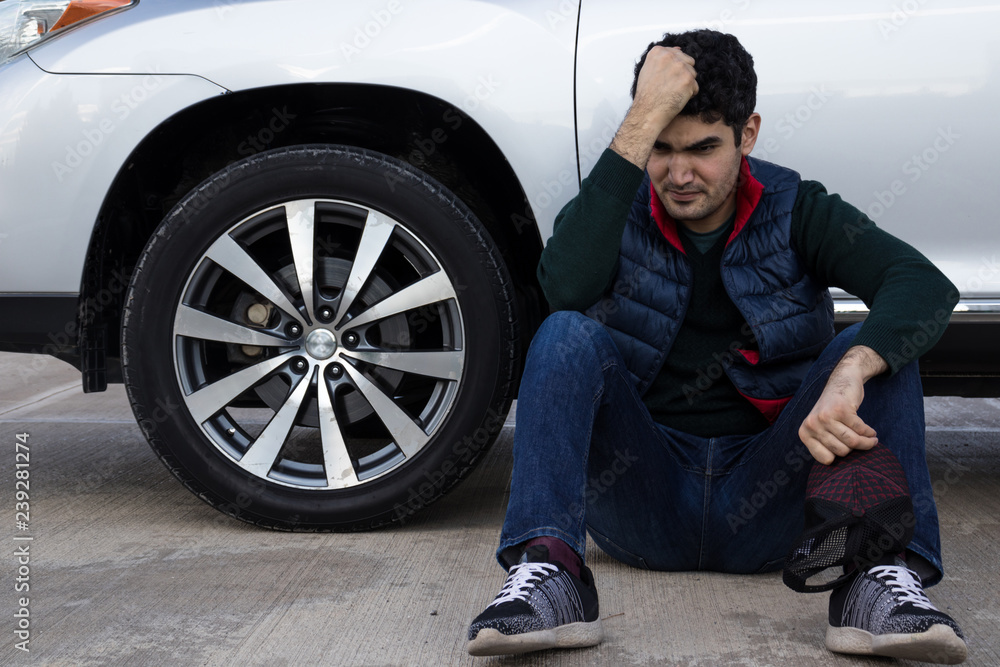 depressed man sitting on a ground leaning on his broken car. Sad, angry ...
