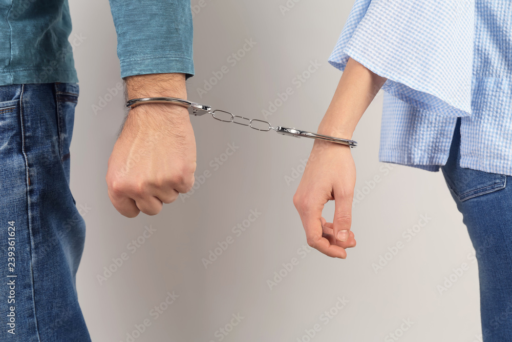 Couple with handcuffed together hands on light background. Concept of ...