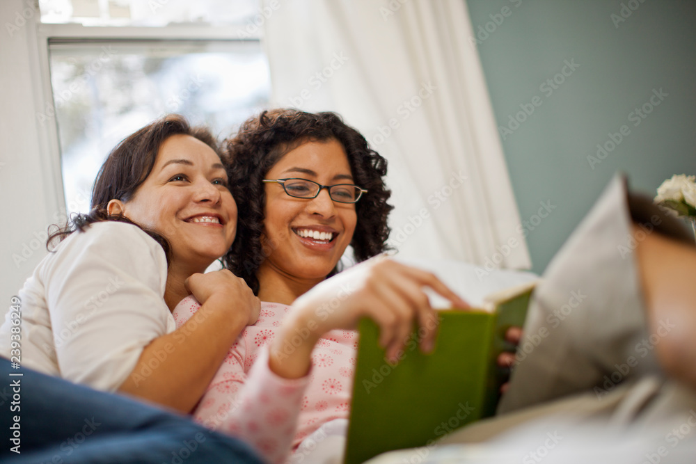 Smiling friends reading in bed together. Stock Photo | Adobe Stock