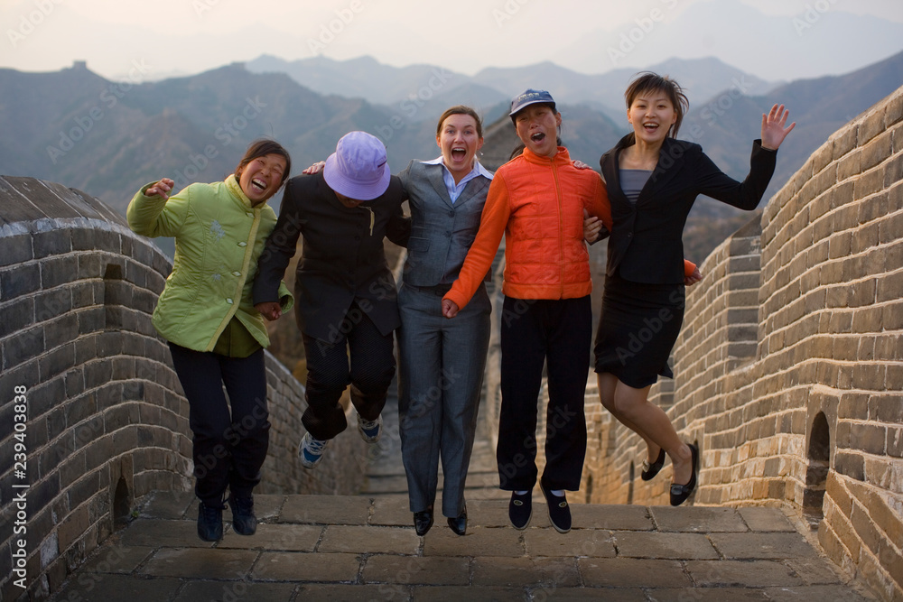 Group of women jumping for a photo at the Great Wall Of China. Stock ...