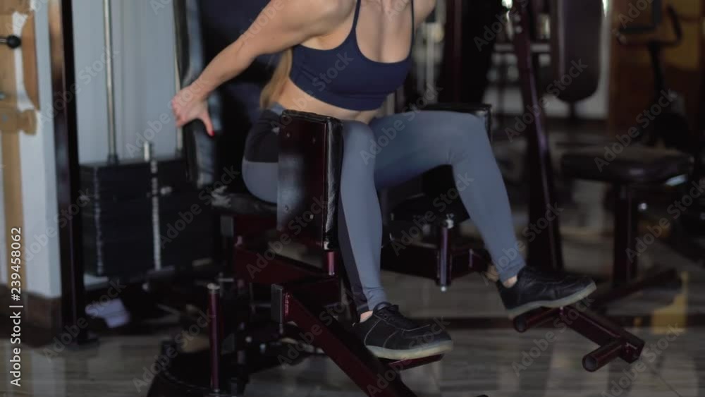 Close-up shot of girl's legs, working out on leg abduction machine ...