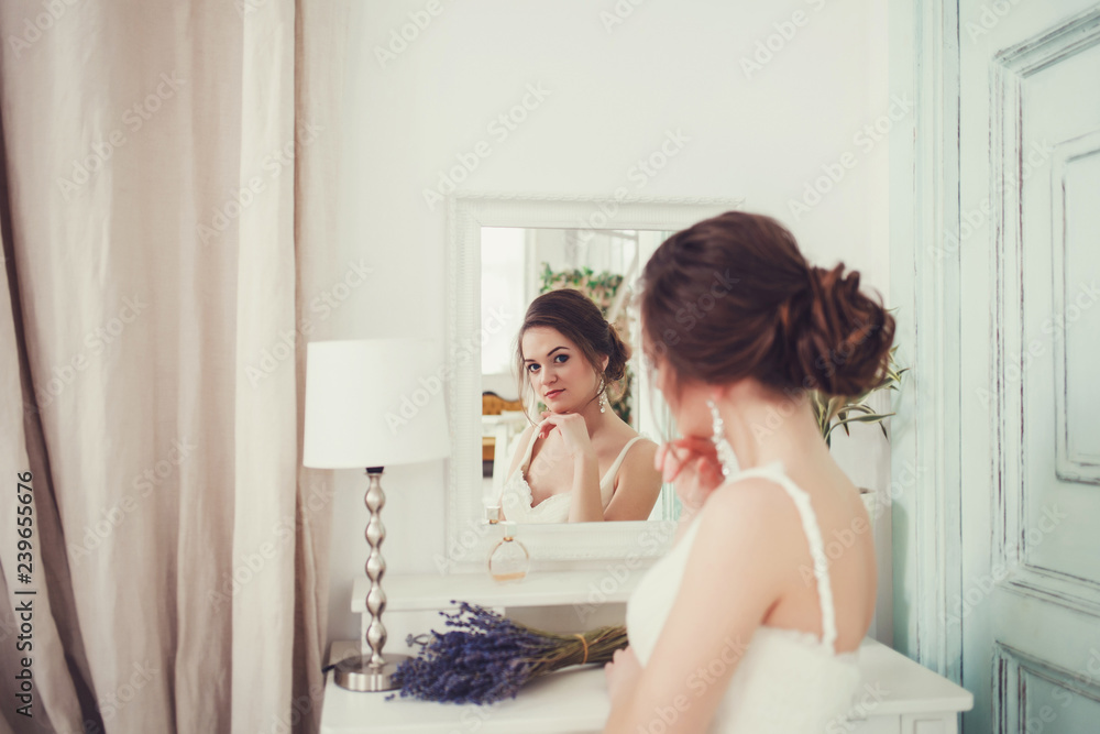 beautiful bride brunette sitting in the mirror and preparing for the ...