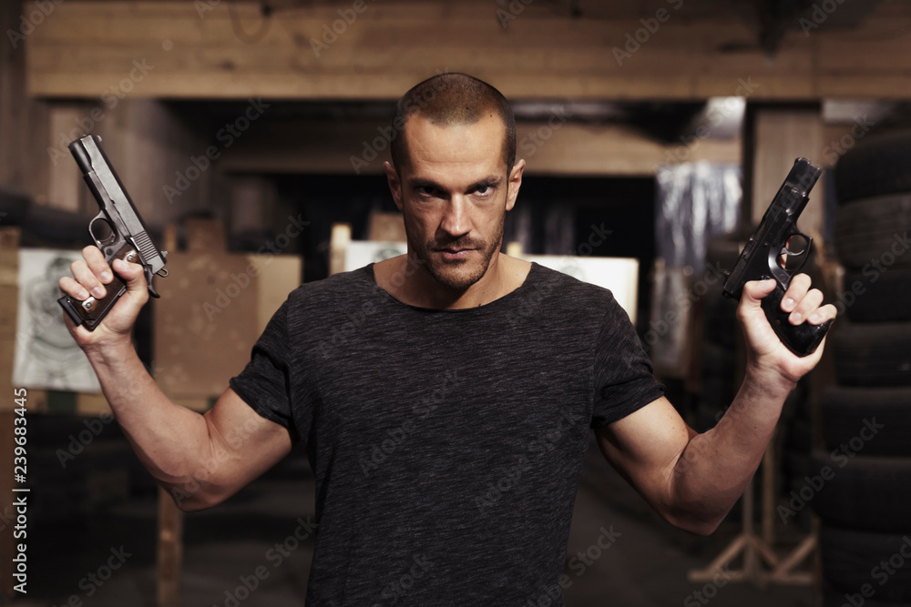 Portrait of man with guns standing in shooting range Stock Photo ...