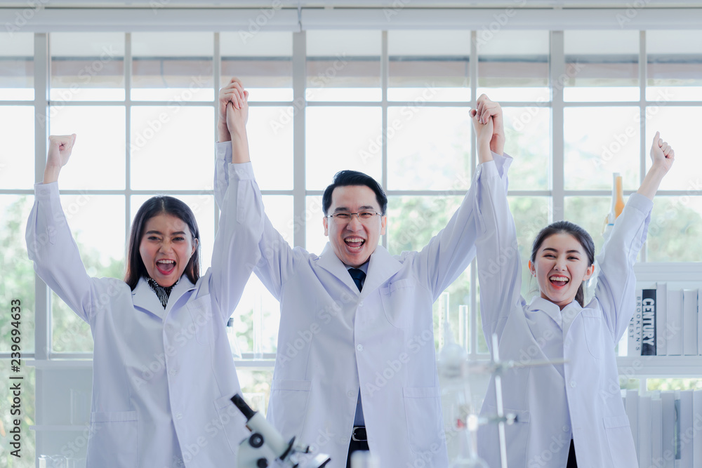 The powerful scientists hold hands raised in colleague lab. They are ...