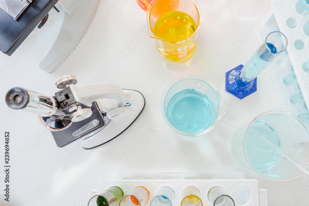 Closed up microscope with tube glass and beaker in laboratory. Blue ...