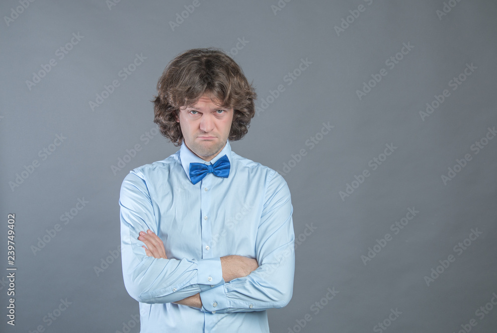 Resentful man with arms folded over gray background in studio shot and ...