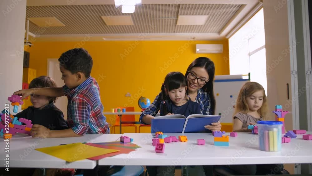 Positive mixed race daycare teacher and diverse multicultural kids ...