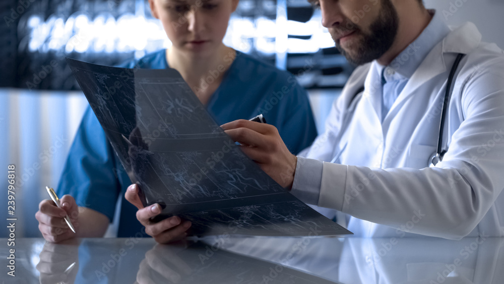 Neurosurgeon and nurse watching cerebral vessels x-ray before operation ...