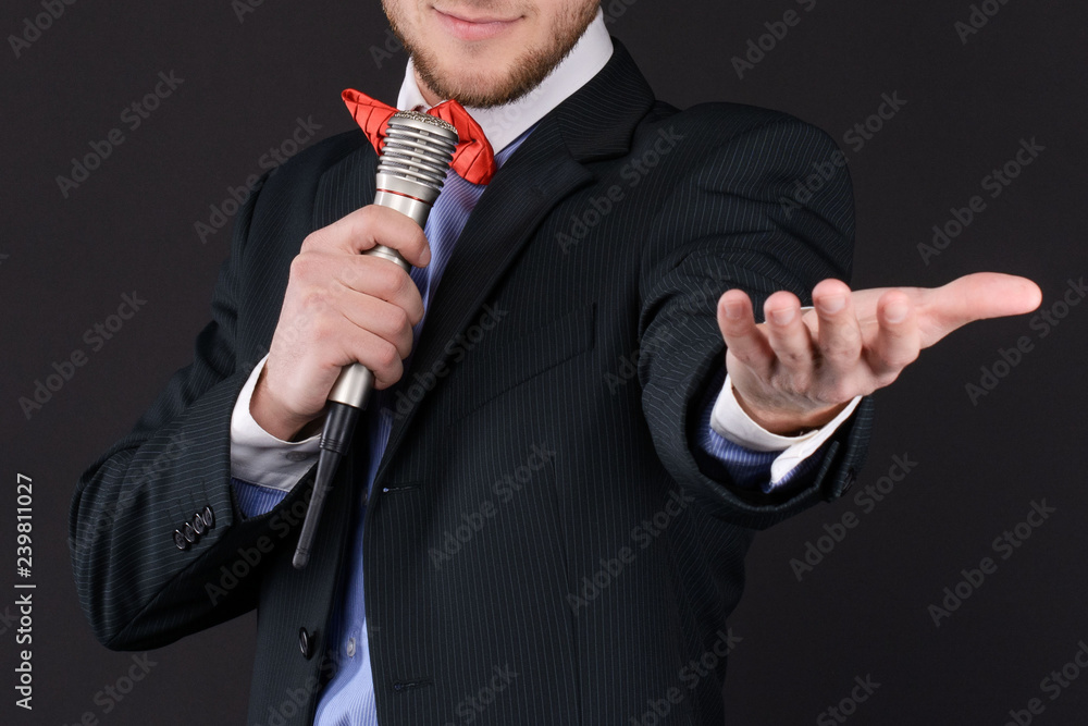 Handsome Master of ceremonies in black suit holding microphone in hand ...