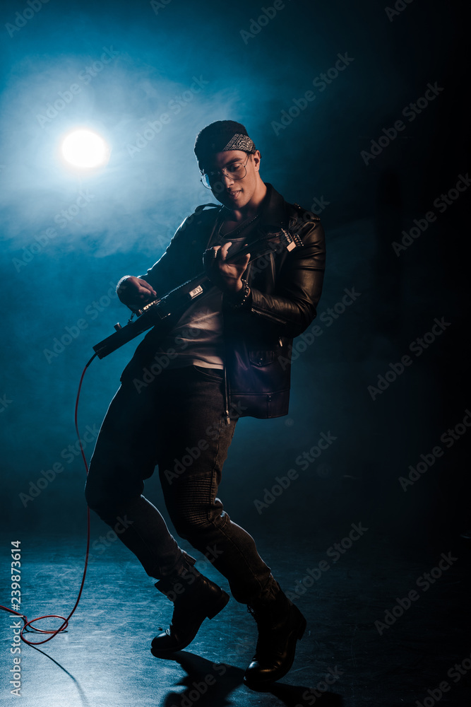concentrated male rock star in leather jacket performing on electric ...