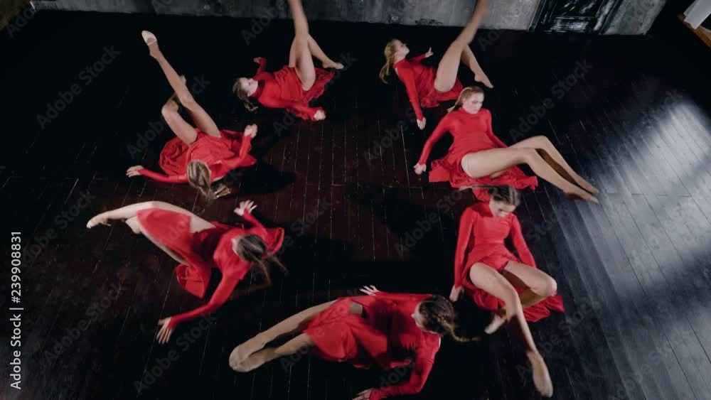 seven female dancers are lying on a floor in round figure, moving and ...