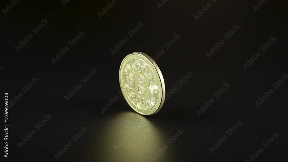Golden Bitcoin (real coin, minted) turning on rotary disc. The centered ...