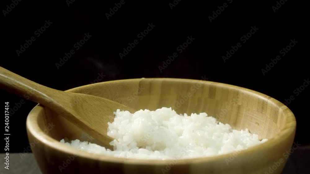 Close up for steamed rice in a wooden bowl with wooden stirring spoon ...