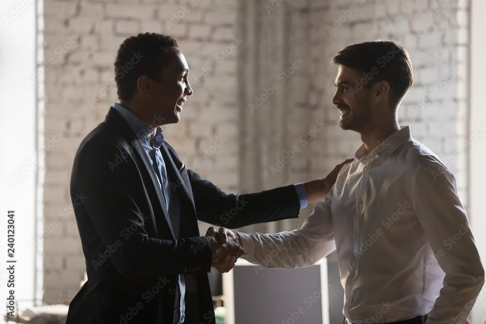 African executive manager handshaking caucasian employee promoting ...