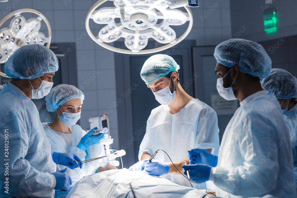 Urgent surgery. Professional smart intelligent surgeons standing near ...