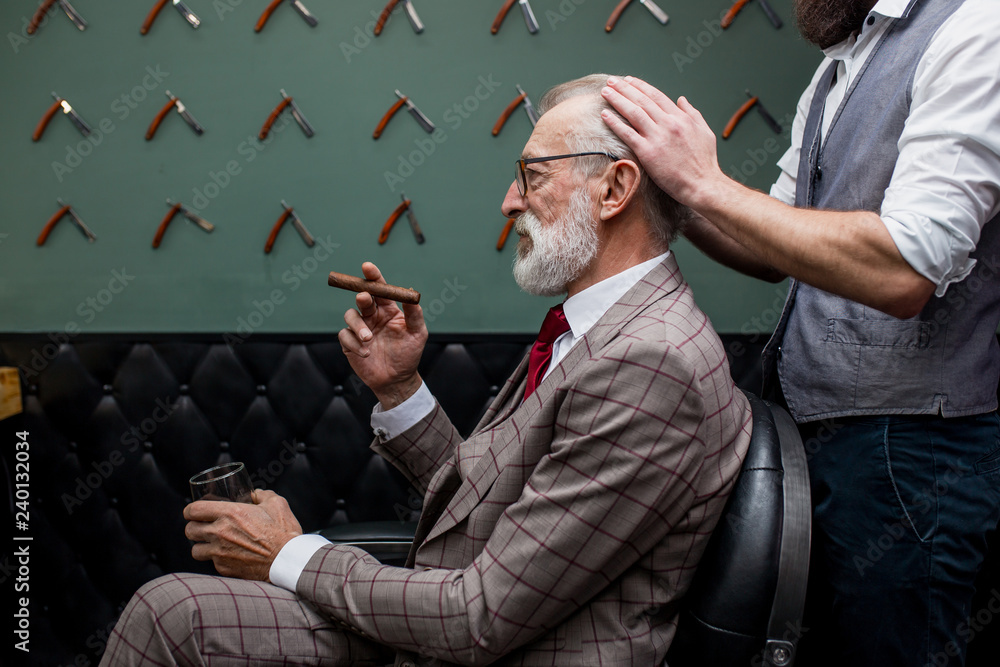 Barber brushes grey hair of respectable old male client dressed in ...