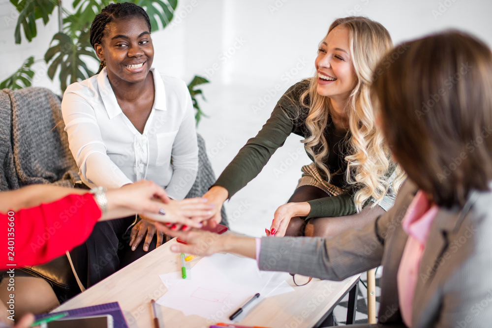 Motivated excited multiracial female team giving high five celebrating ...