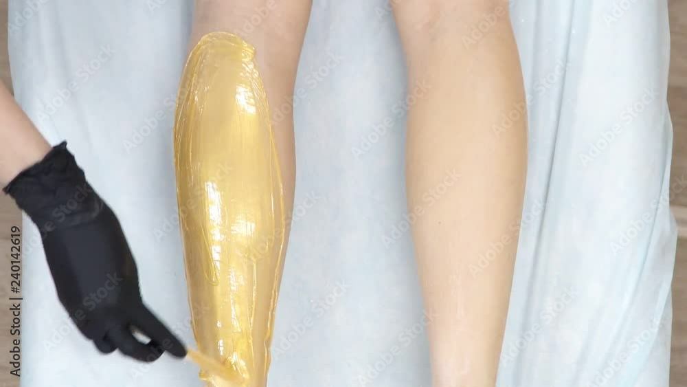 The beautician works with the paste and removes the hairs on the legs ...