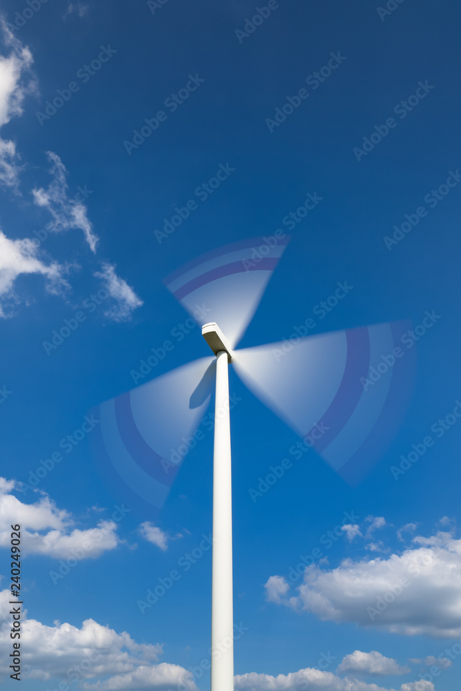 A rotating wind turbine and blue sky with clouds. Large three-bladed ...