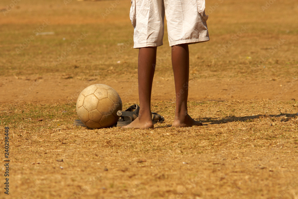 Young captain of a football team standing barefoot in the goal after ...