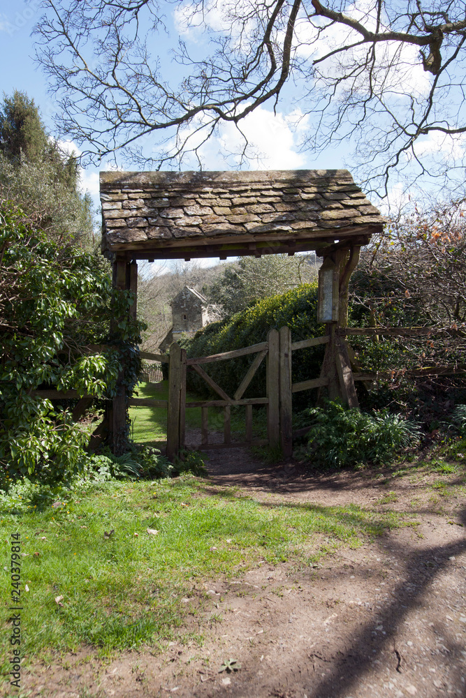 The picturesque old lychgate frames the tiny old Saxon church in spring ...