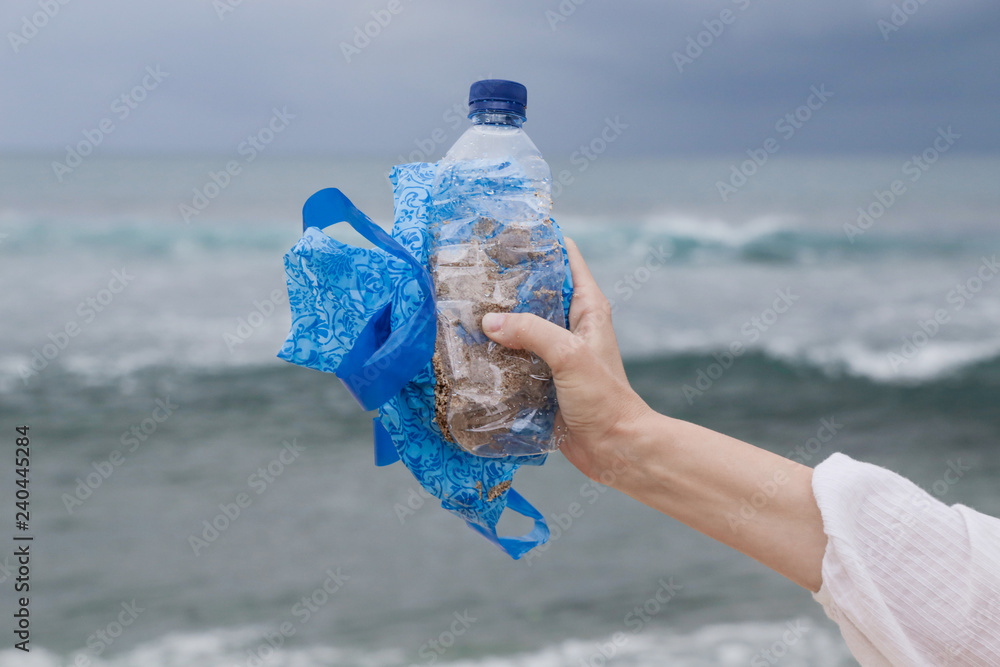 Plastic waste in hand against the blue sky background. The action of ...