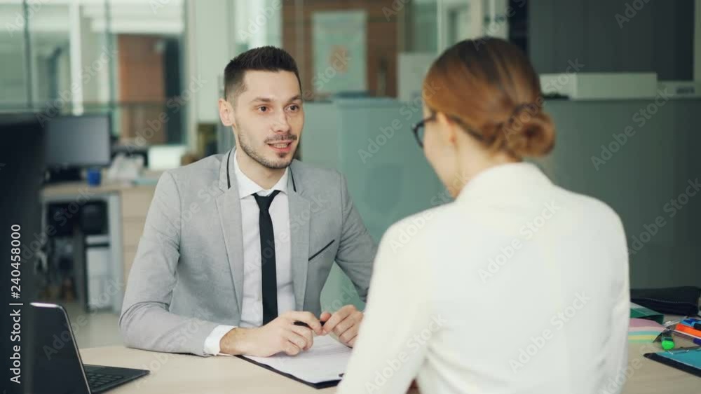 Smiling young man recruiter is talking to young woman successful ...