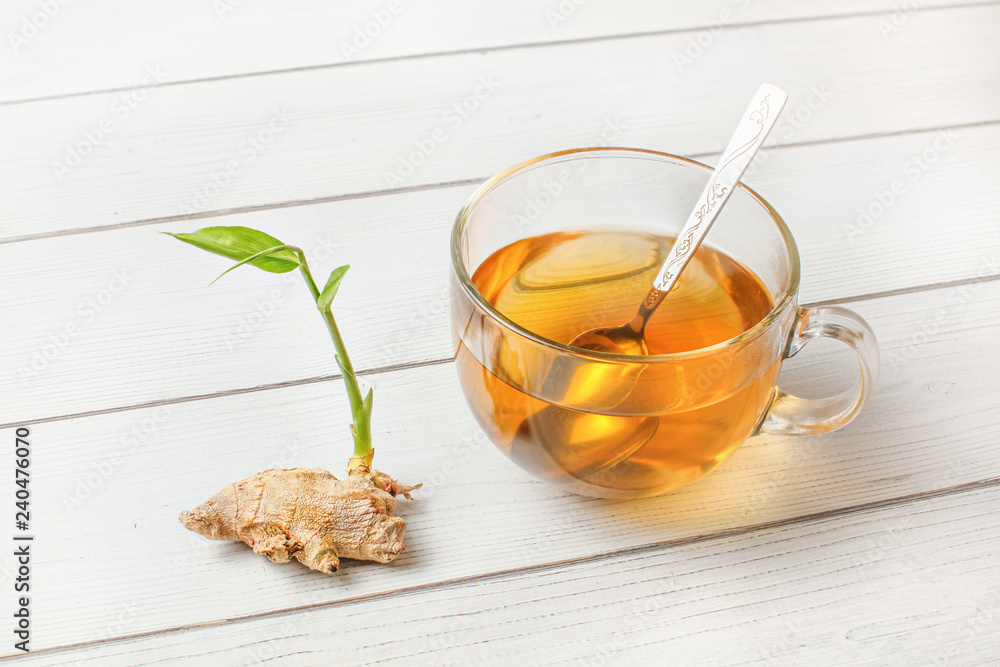 Glass cup of freshly brewed amber tea, dry ginger root with green ...