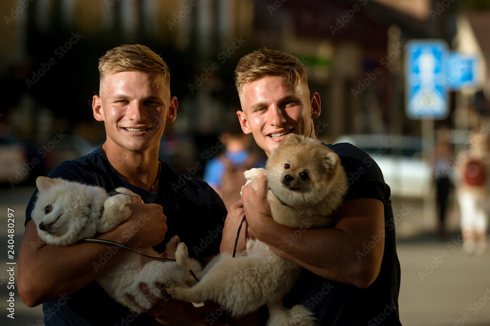 Dogs bring them joy. Muscular men with dog pets. Happy twins with ...