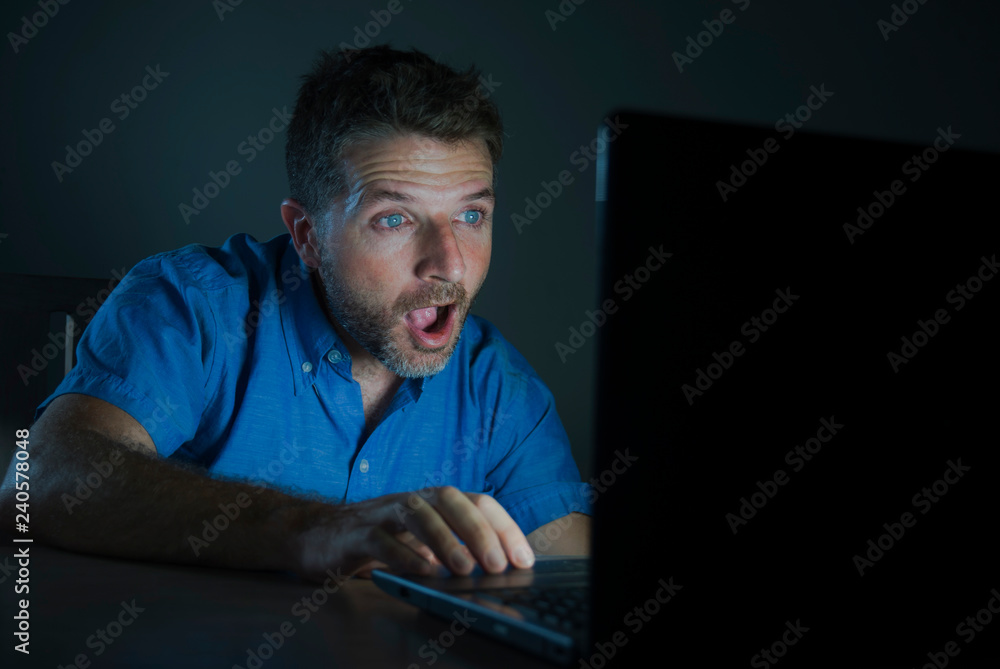 surprised and shocked man at night working with laptop computer in the ...