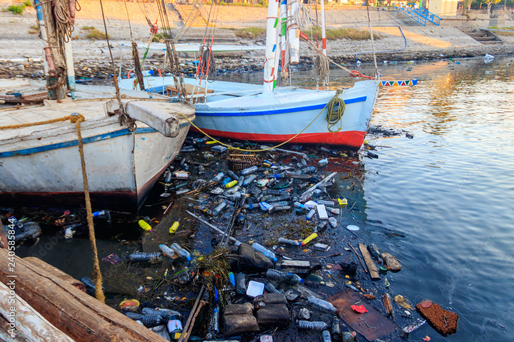 Old boats moored in dirty harbour. Pollution of river, sea, ocean water ...