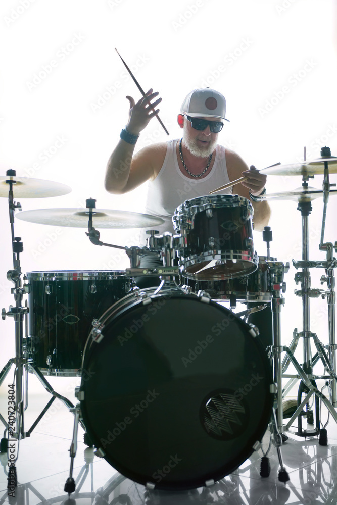Professional drummer behind the drum kit on a white background in shirt ...