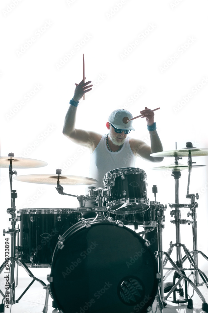 Professional drummer behind the drum kit on a white background in shirt ...