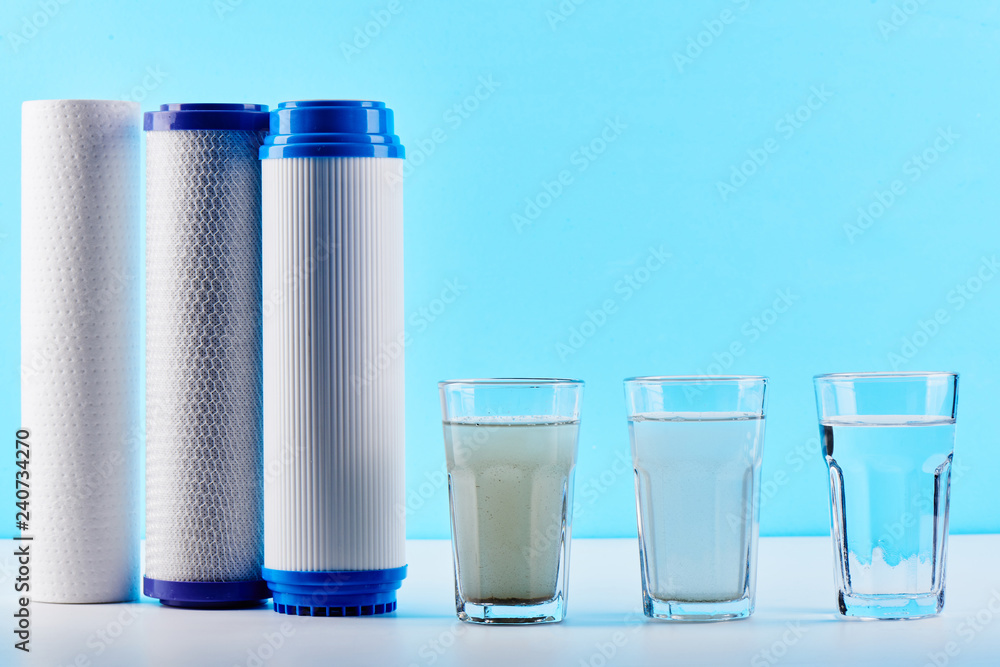 Water filters concept. Carbon cartridges and a three glasses on a white ...