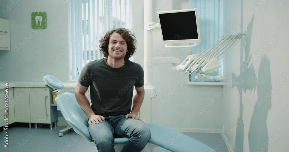 Happy and smiling patient young guy with perfect teeth sitting in the ...