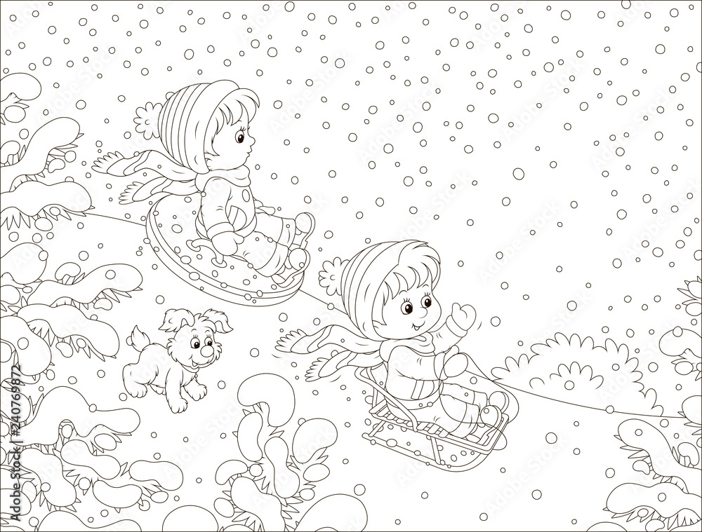 Small children sledding down a snow hill in a snow-covered winter park ...