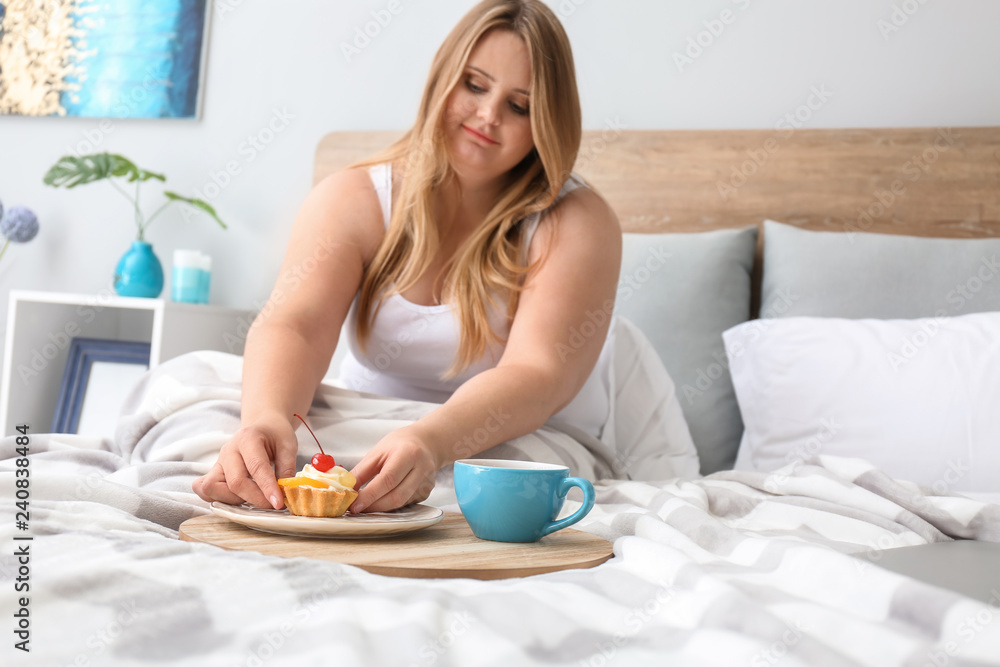 Beautiful plus size girl with breakfast sitting on bed in morning ...