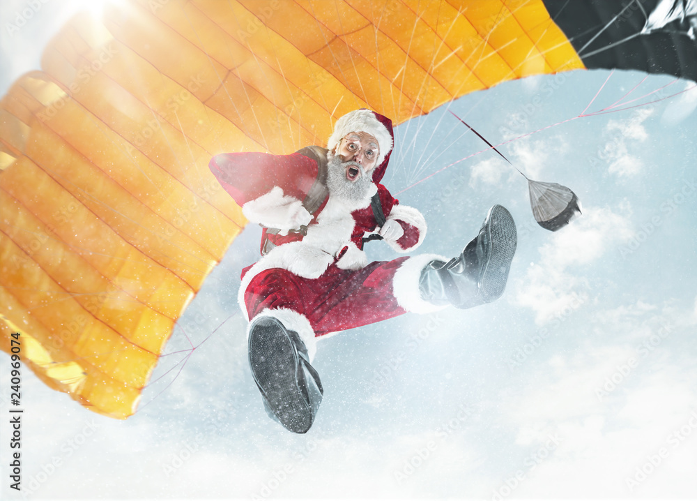 Merry Christmas and happy holidays. Santa Claus flying with parachute ...