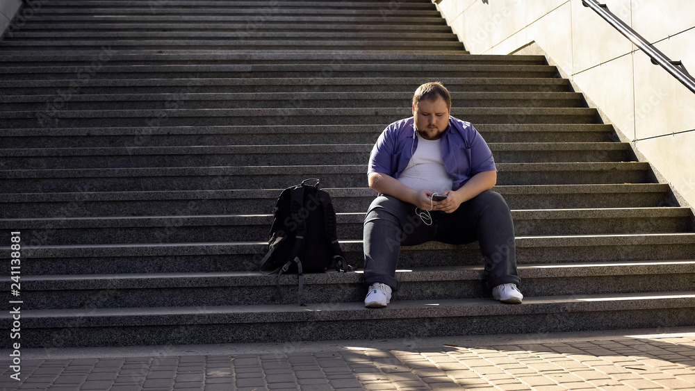 Fat man listening to music on stairs, loneliness, overweight causes ...