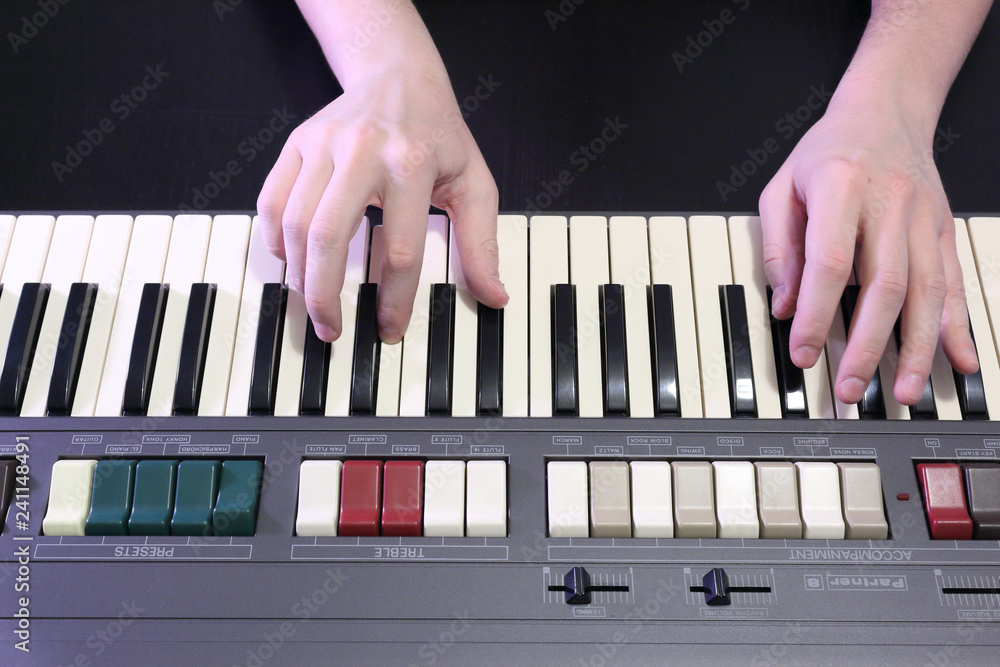 A right hand playing a C# sharp (DO#) major chord on an old black piano ...