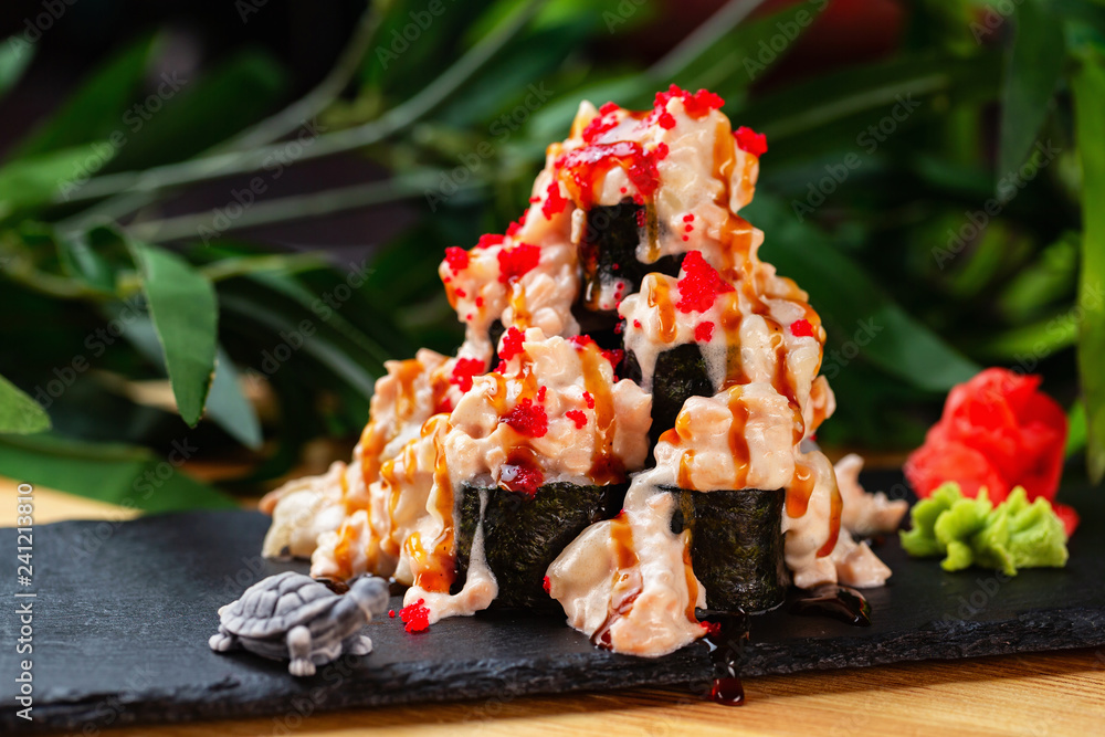 Plate of volcano sushi rolls with lava sauce at decorated with green ...