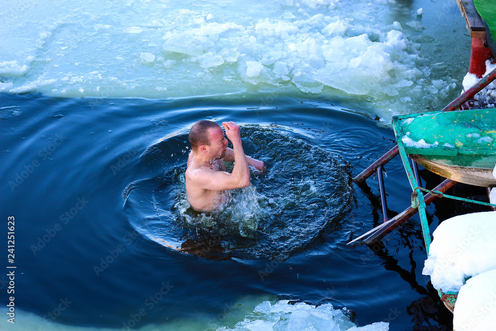 Christian rite of baptism. A man dives into the ice hole and baptizes ...