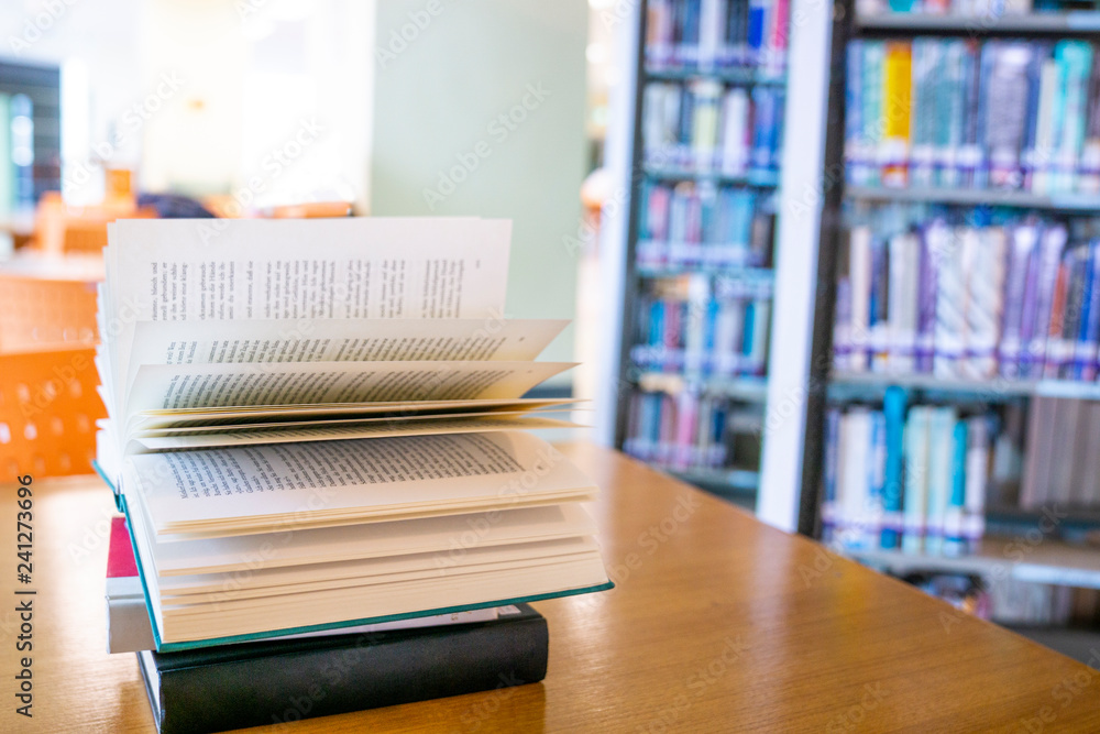 Learning concept with opening book in library, isle of bookshelves in ...