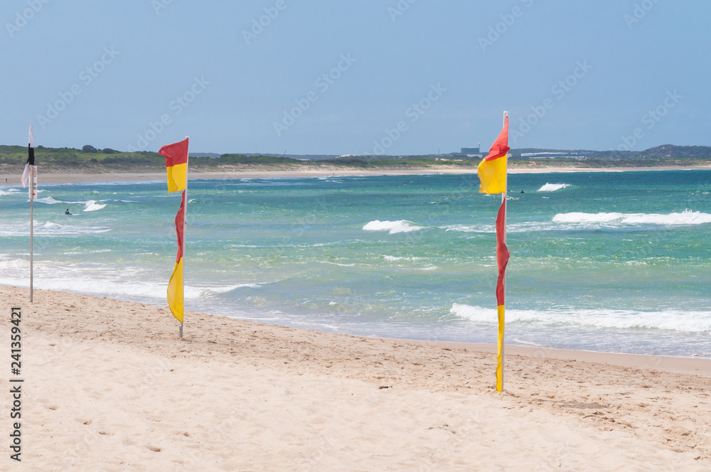 Red and yellow flags on patrolled beach indicating safe to swim area ...