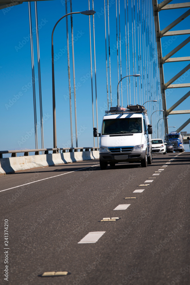 Small compact cargo mini van with ladders on the roof running on arched ...