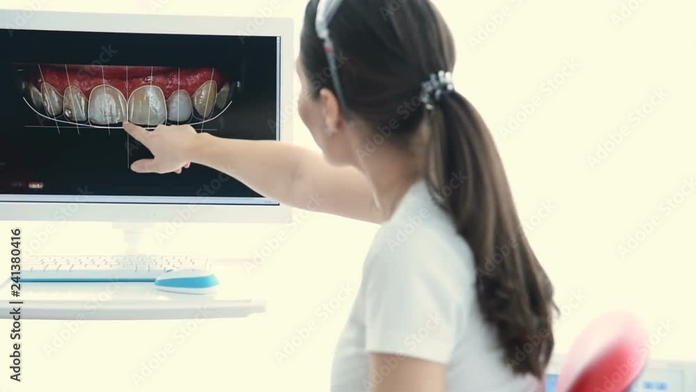The dentist displays a picture of the patient's teeth on the monitor ...