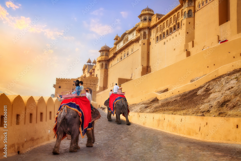 Tourist couple enjoy elephant ride at the historic Amer Fort at sunset ...