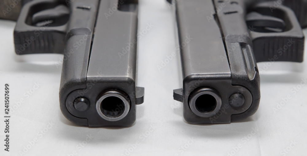 Two black semi automatic pistols, a 9mm and a 40 caliber on a white ...