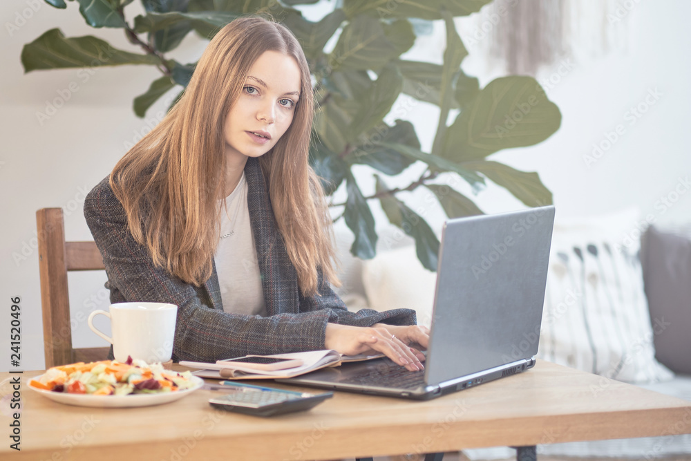 Portrait of gorgeous young woman sitting with open laptop computer in ...