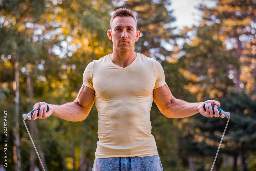 Sporty young man jumping rope in park Stock Photo | Adobe Stock